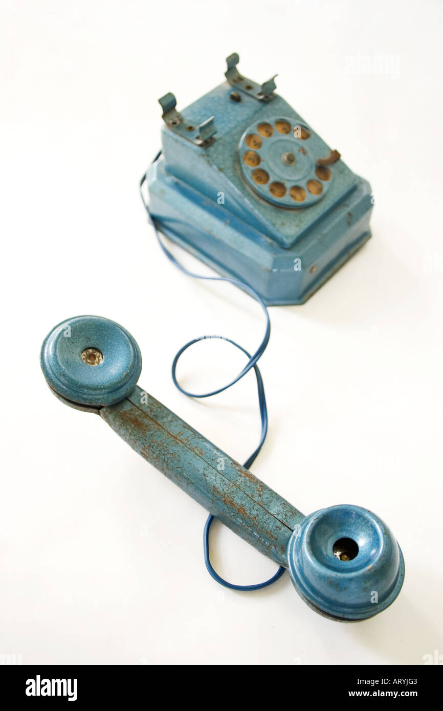 Blue antique tin toy telephone with receiver off the hook. Focus is on ...
