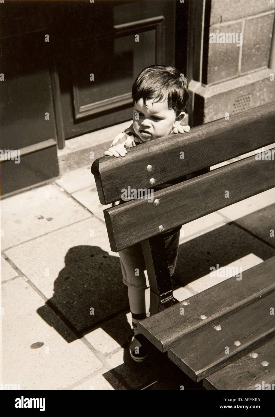 Young boy standing behind a bench Stock Photo - Alamy