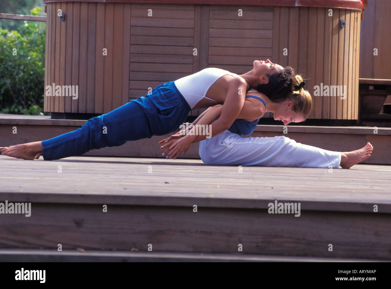 Hatha yoga being performed in the double back stretch position by two ...