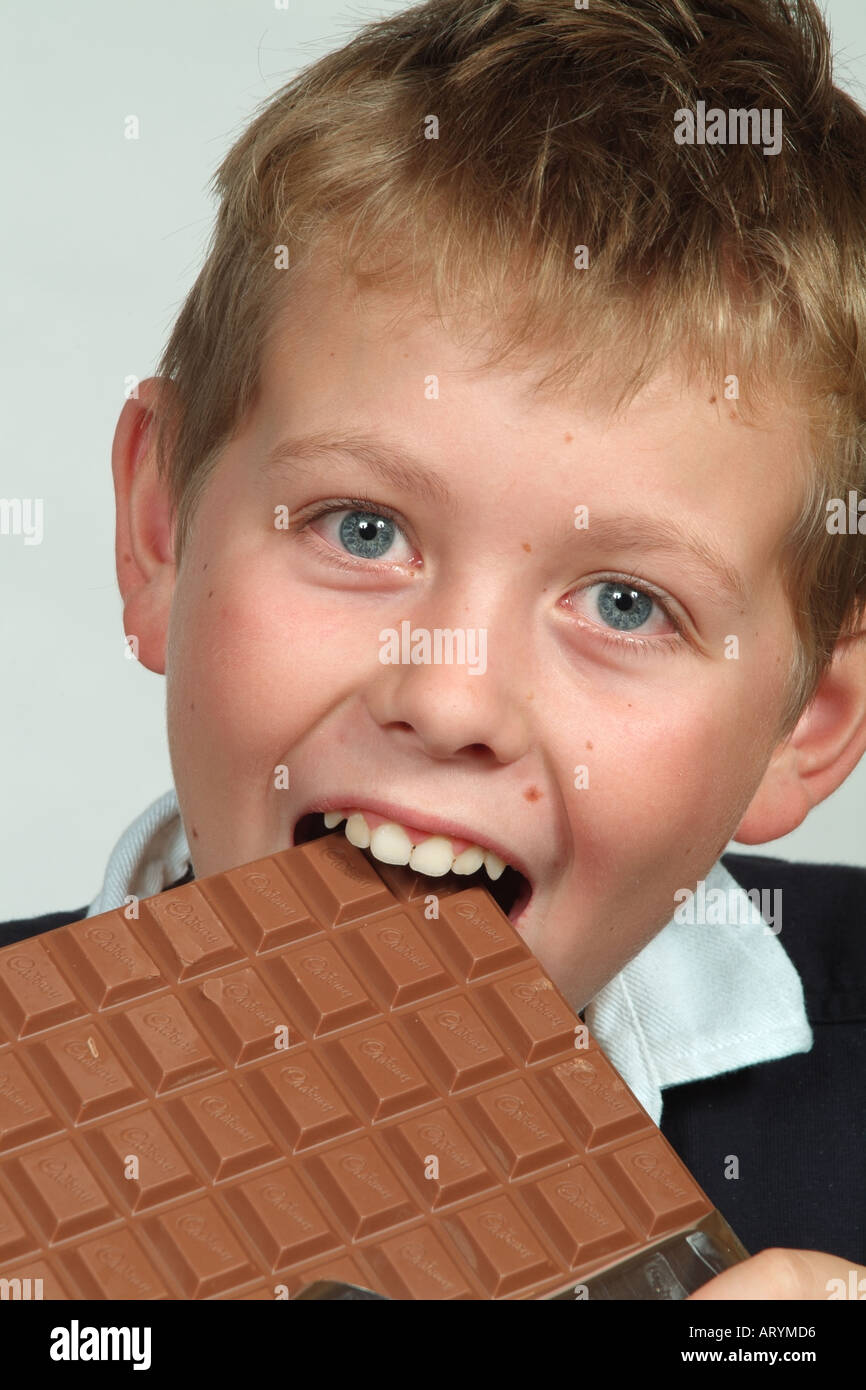 Schoolboy with sweet tooth eating a large bar of chocolate. Boy Stock ...