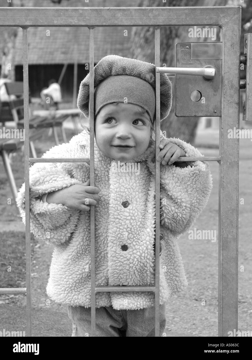 toddler on a playground looking through a gate Stock Photo - Alamy