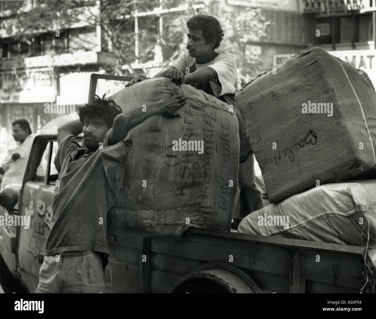 Labourers deliver large heavy parcels to the businessmen who line the ...
