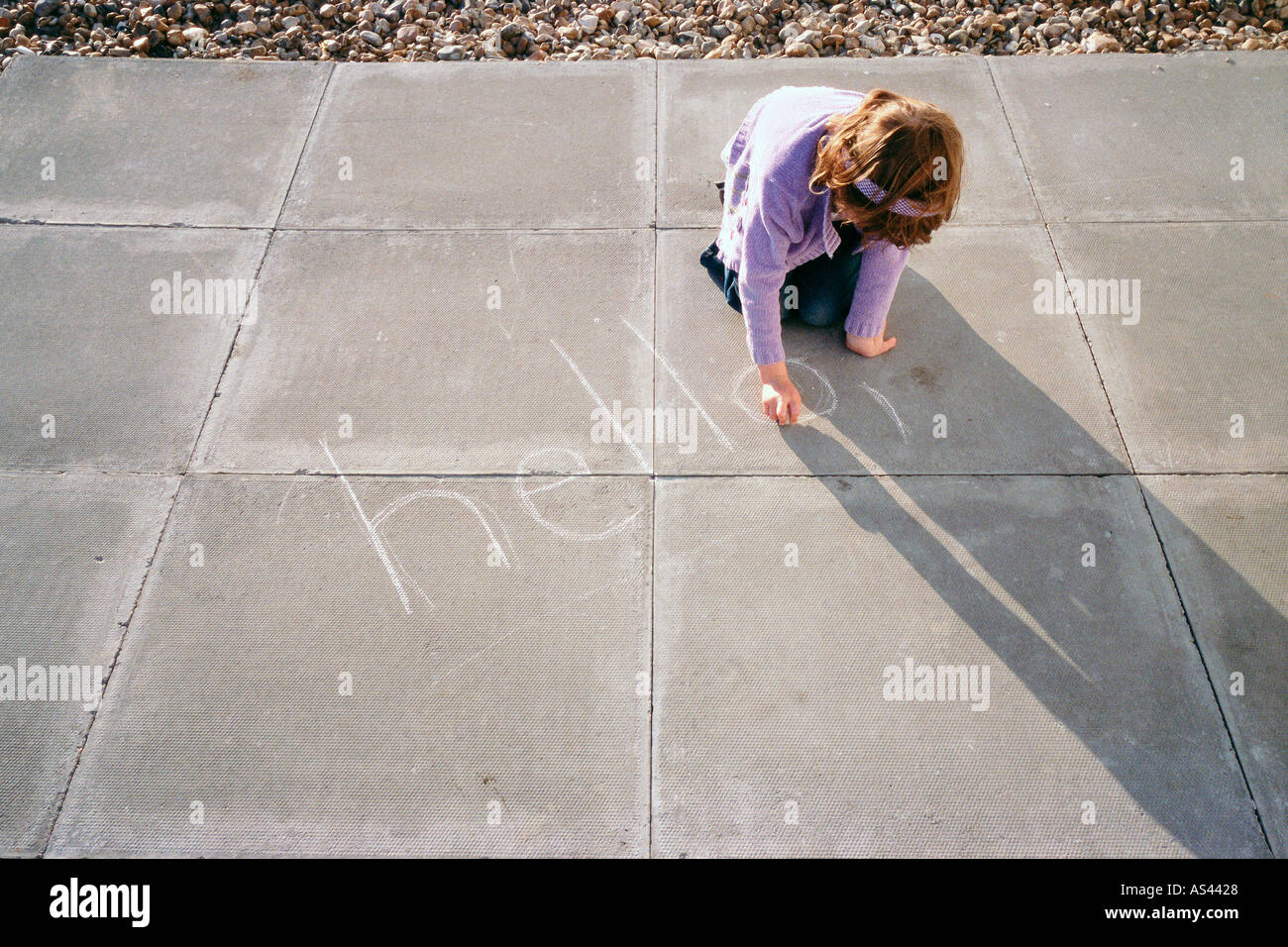 Girl sitting on ground writing Stock Photo - Alamy