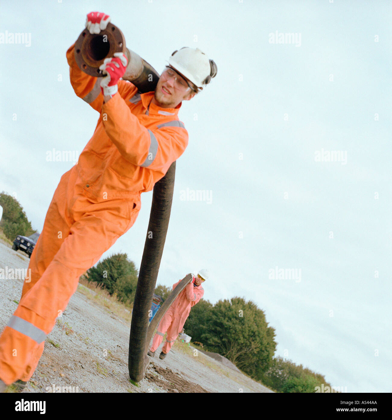 Construction workers carrying a pipe Stock Photo - Alamy