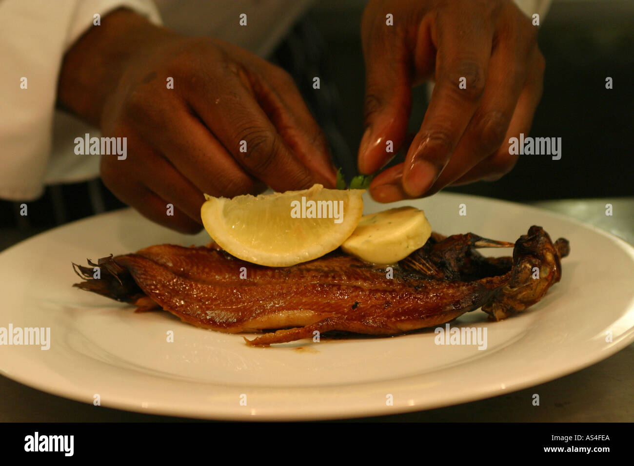 Smoked kippers being prepared by a chef with lemons in a hotel kitchen ...