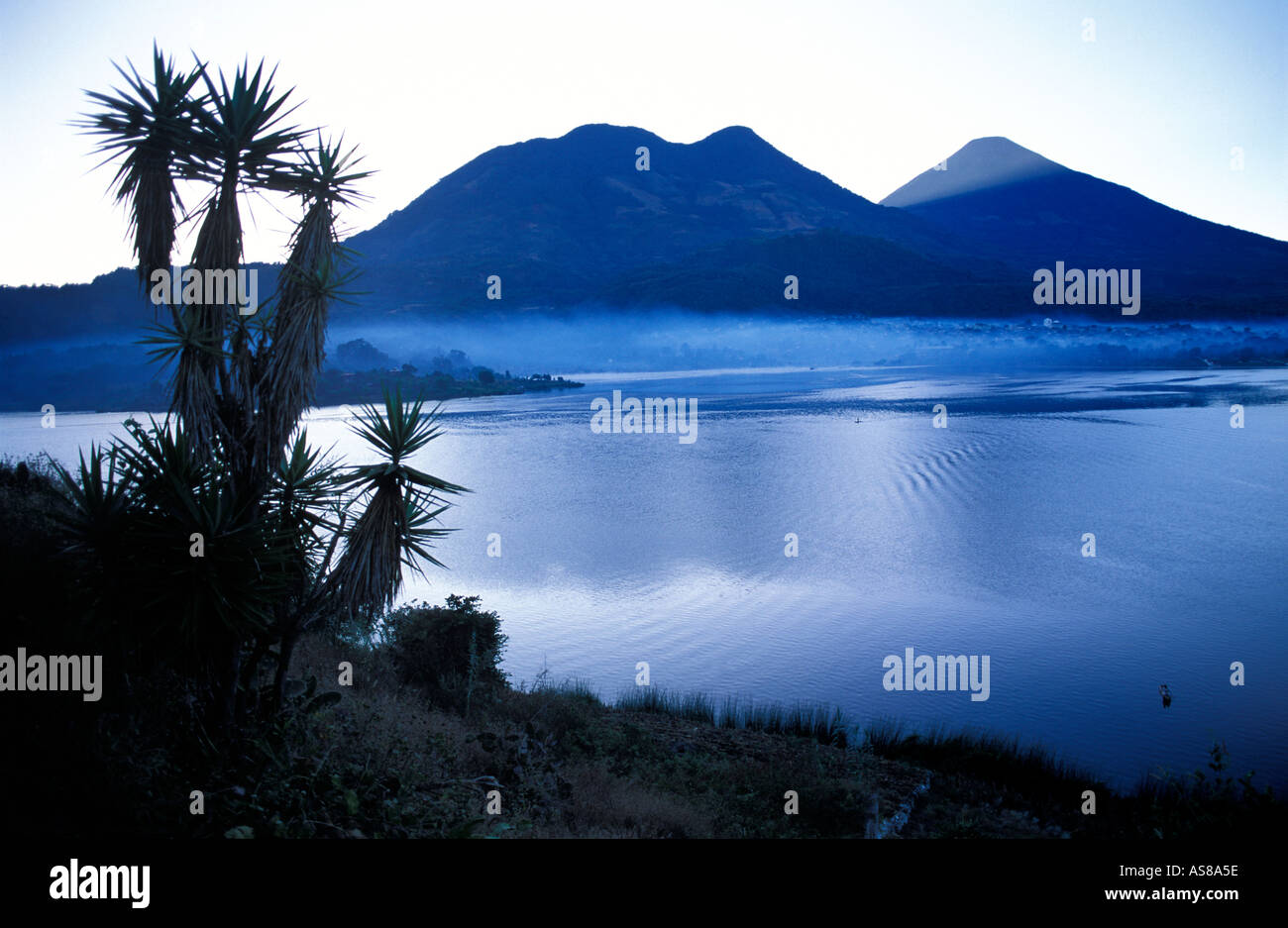 Santiago Atitlan sits beneath the towering peak of Toliman volcano Lake ...