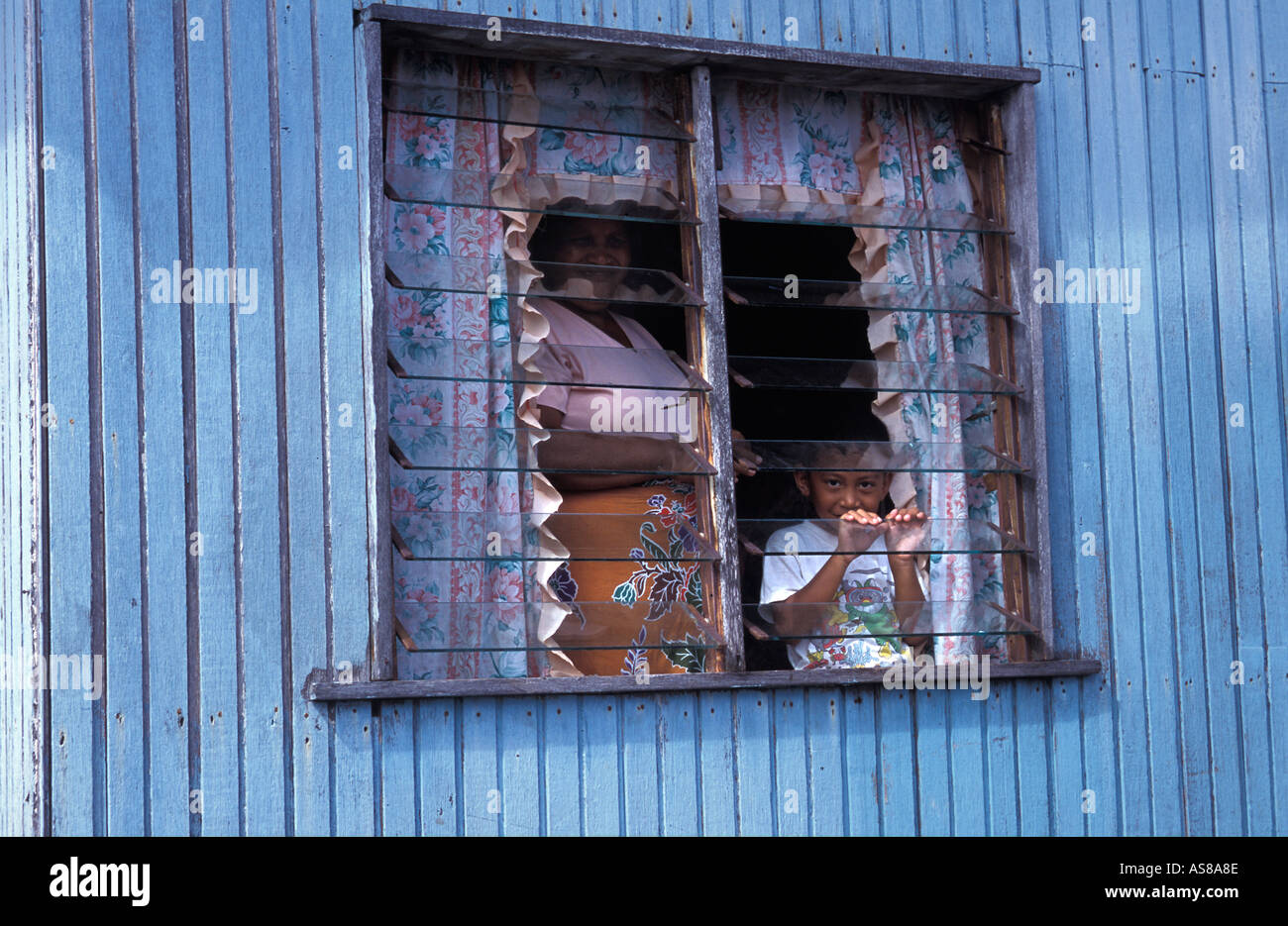 Malaysian woman and son peering out through their window Coastal ...