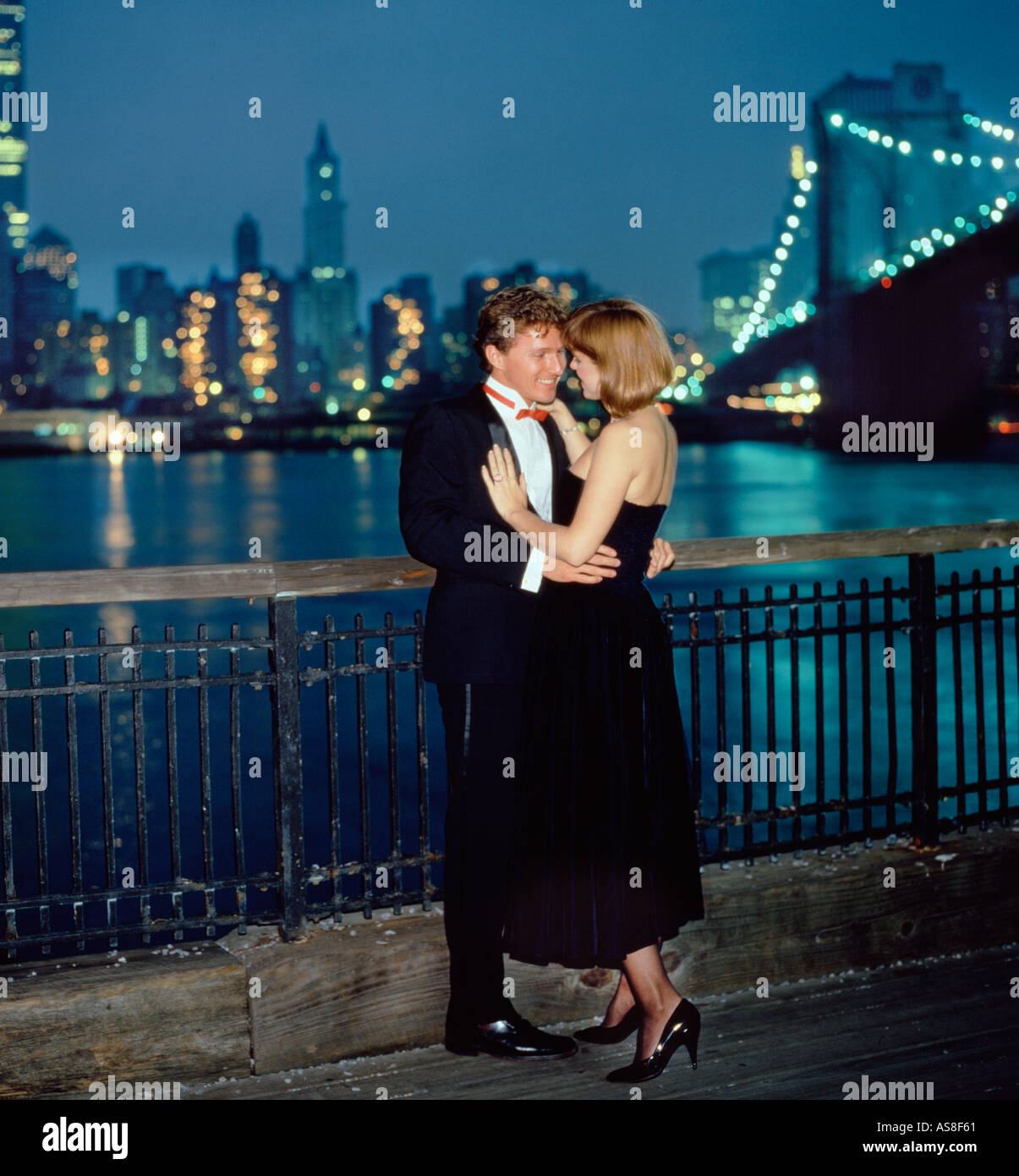 romantic couple embracing on dock with New York City in background at ...