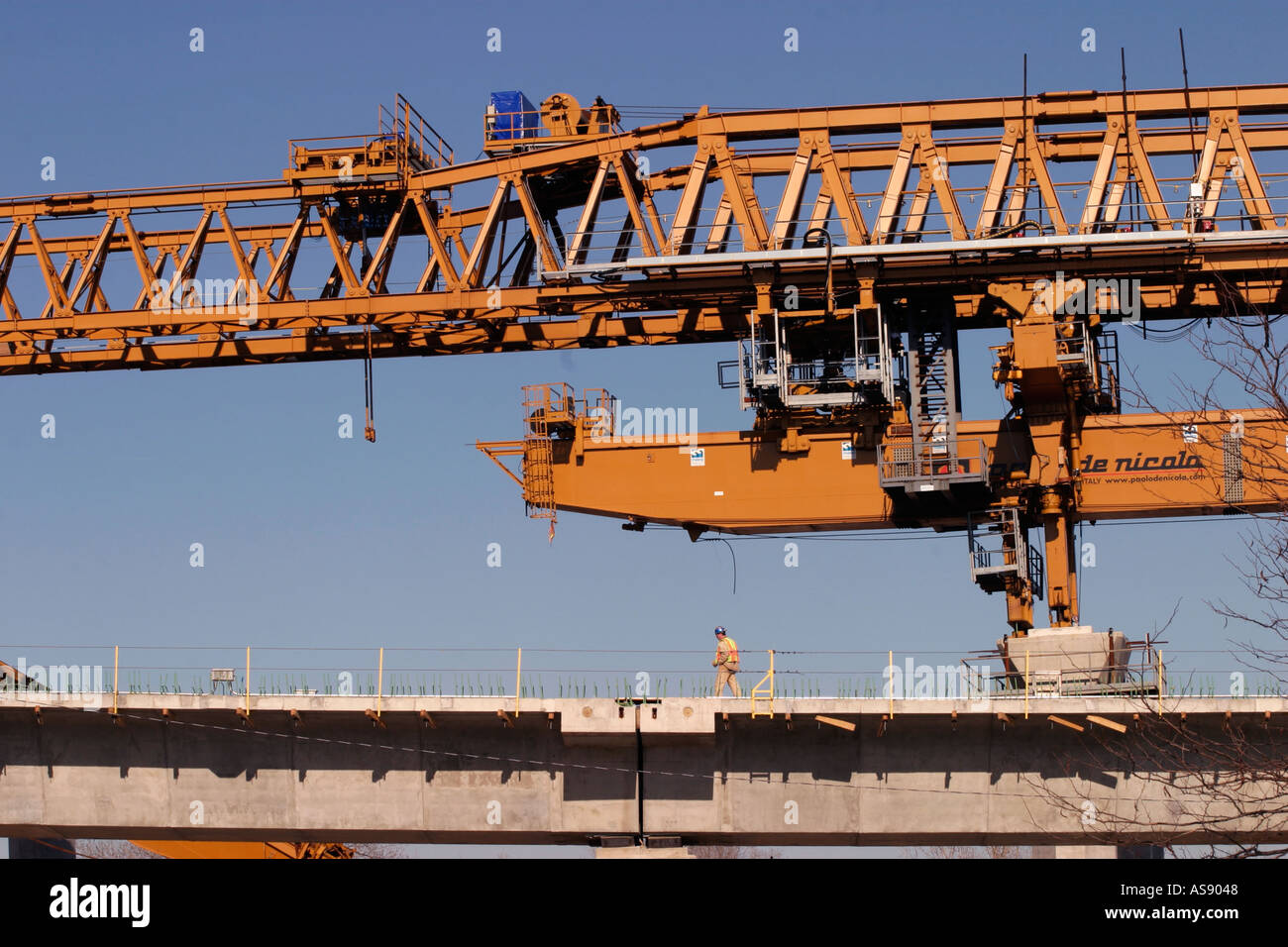 A construction worker walks below an Italian made crane being used in a ...