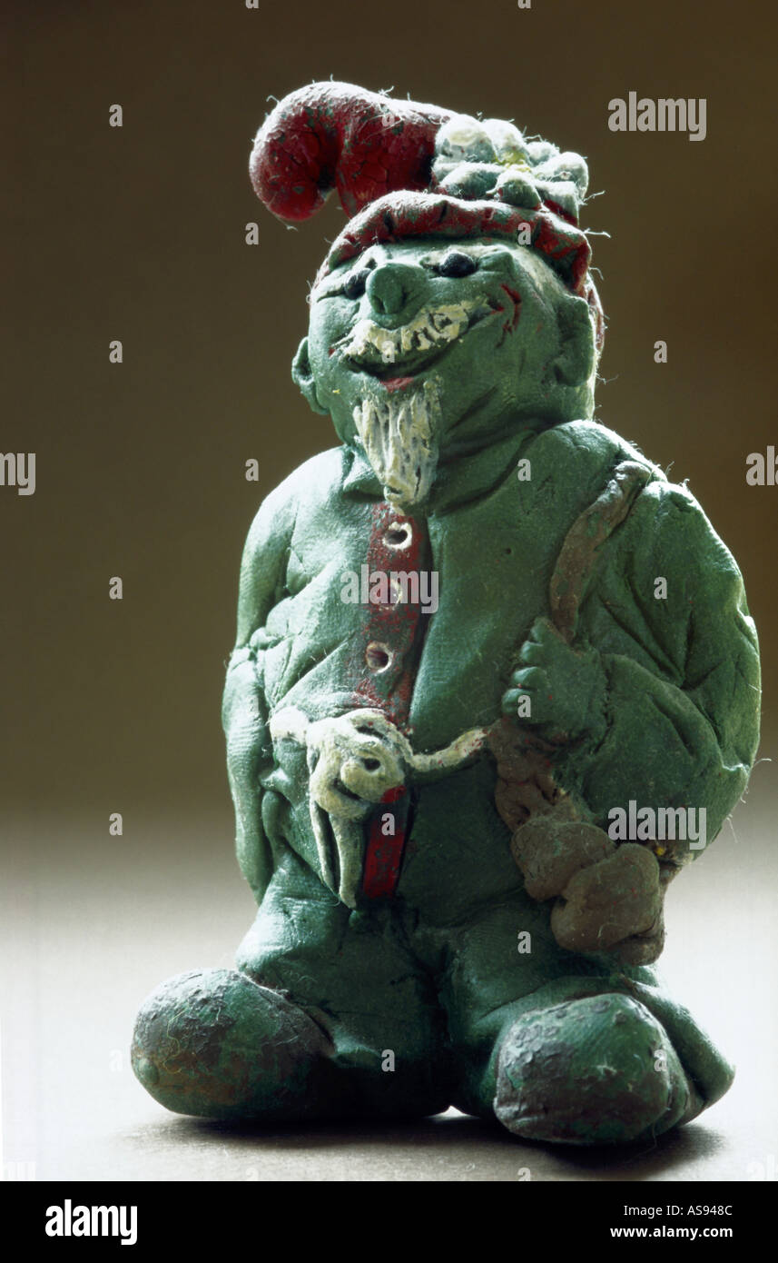 Imp plastic statue with red hat and margerite flower Stock Photo - Alamy