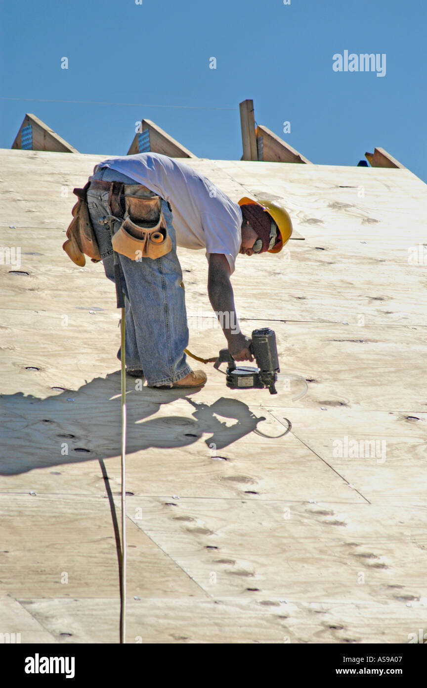Latin Hispanic worker on roof of new building in the sun with pneumatic ...
