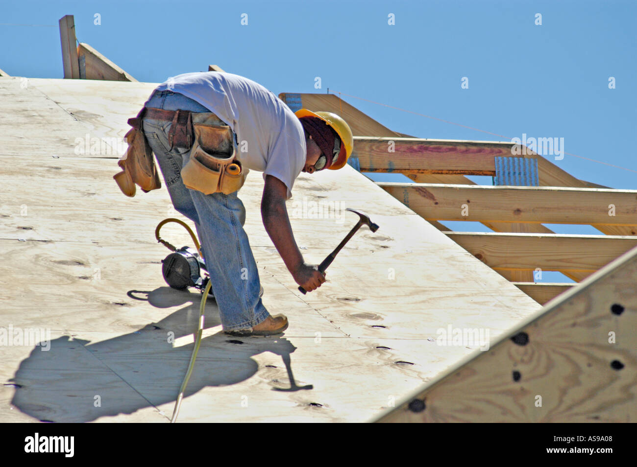 Latin Hispanic worker on roof of new building in the heat of summer sun ...