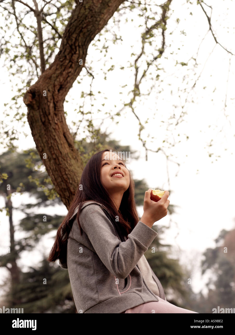 young girl eating apple beside tree Stock Photo - Alamy