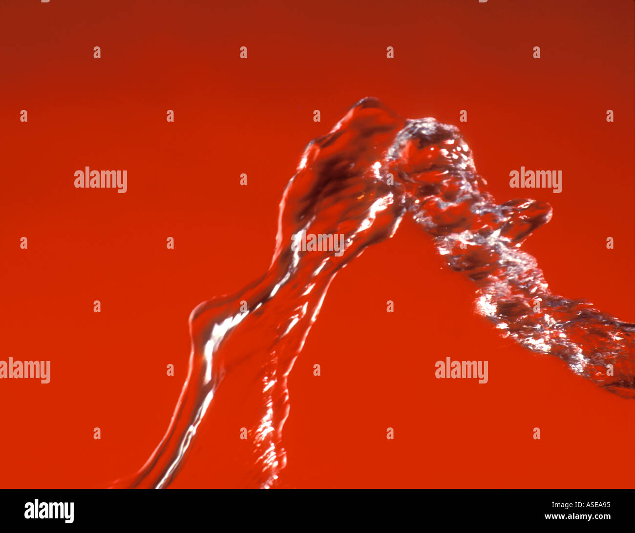 a free form spray or column of water on a red background Stock Photo ...