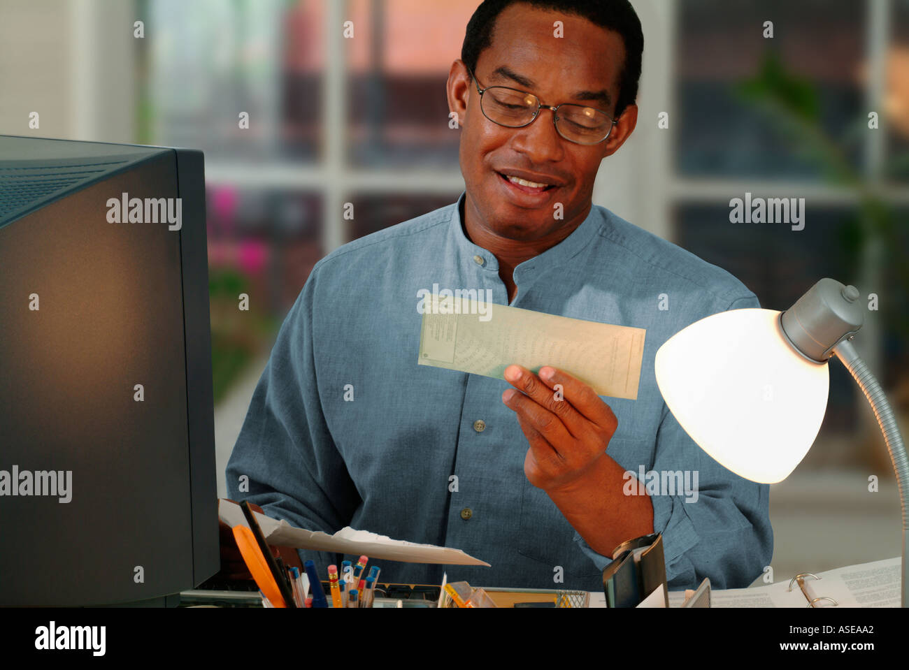 Black man working in a home office and receiving a check in the mail ...