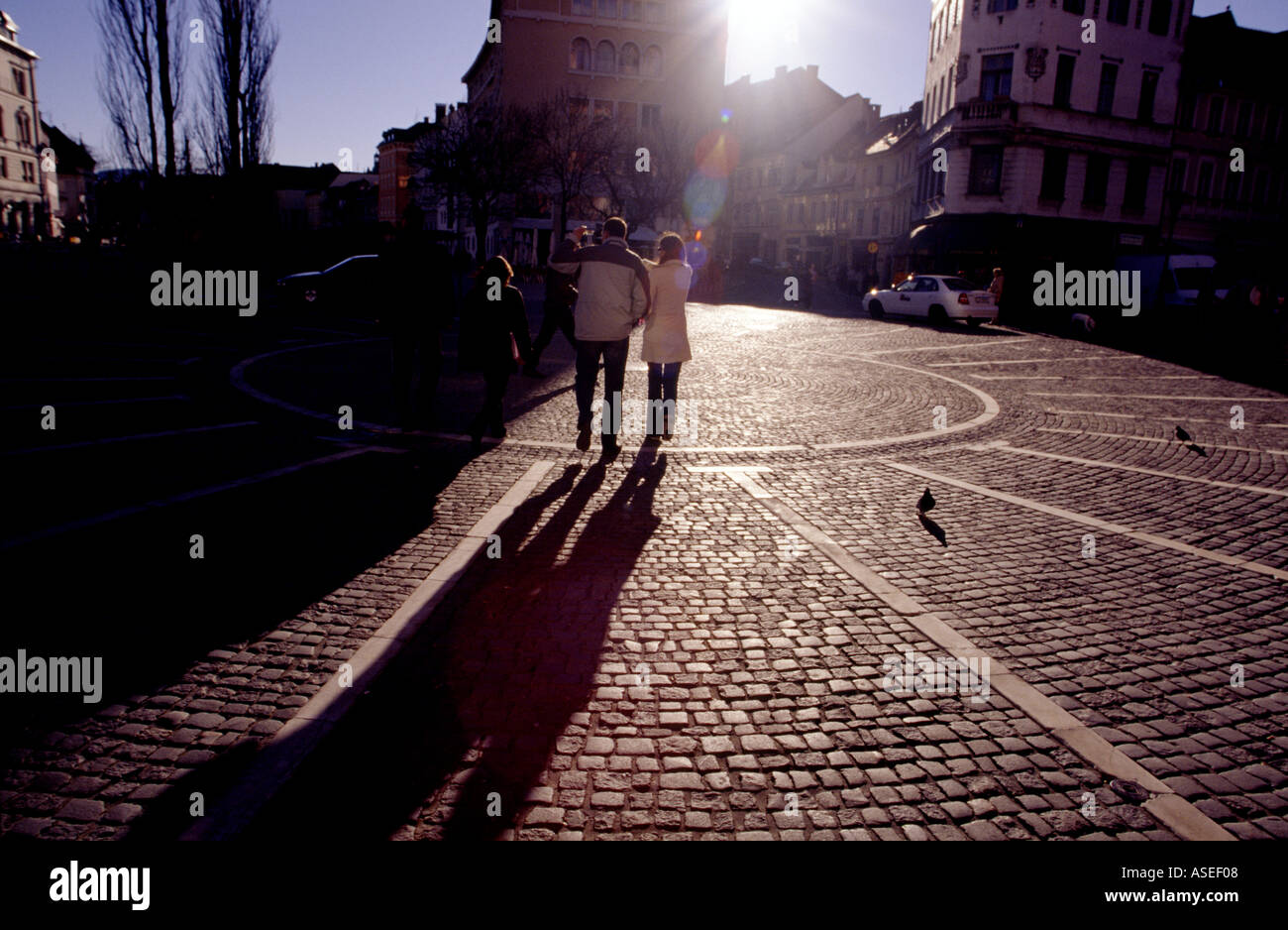 A couple walking close together on a cobblestone plaza as sunset strong ...