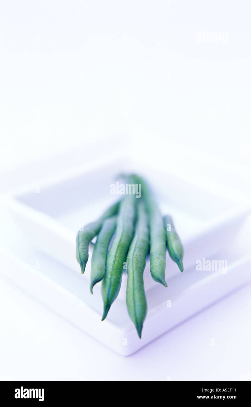 Green fresh string beans tantalisingly hanging over a set of square ...