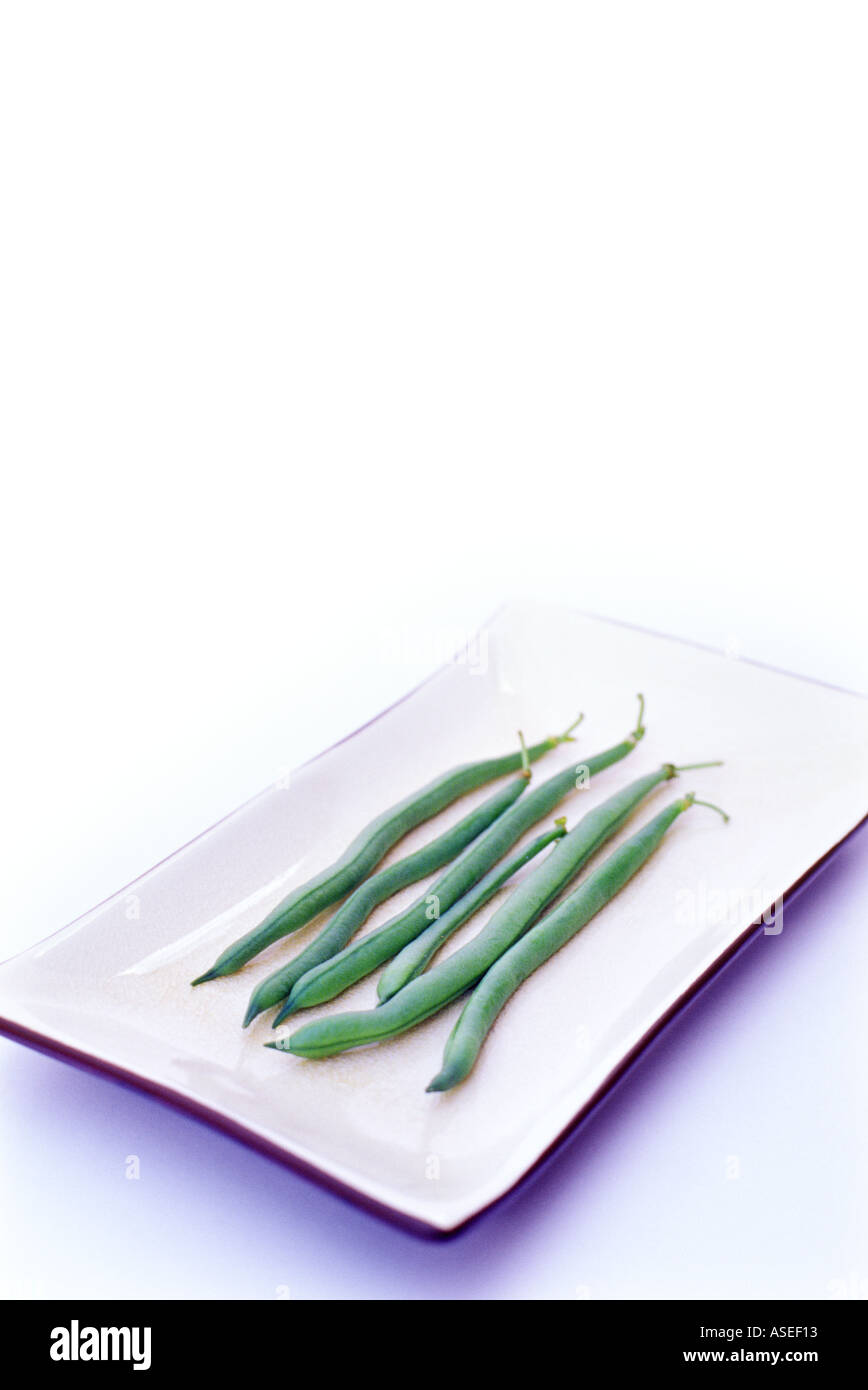 Green fresh string beans laid out on rectangular plate against clean ...