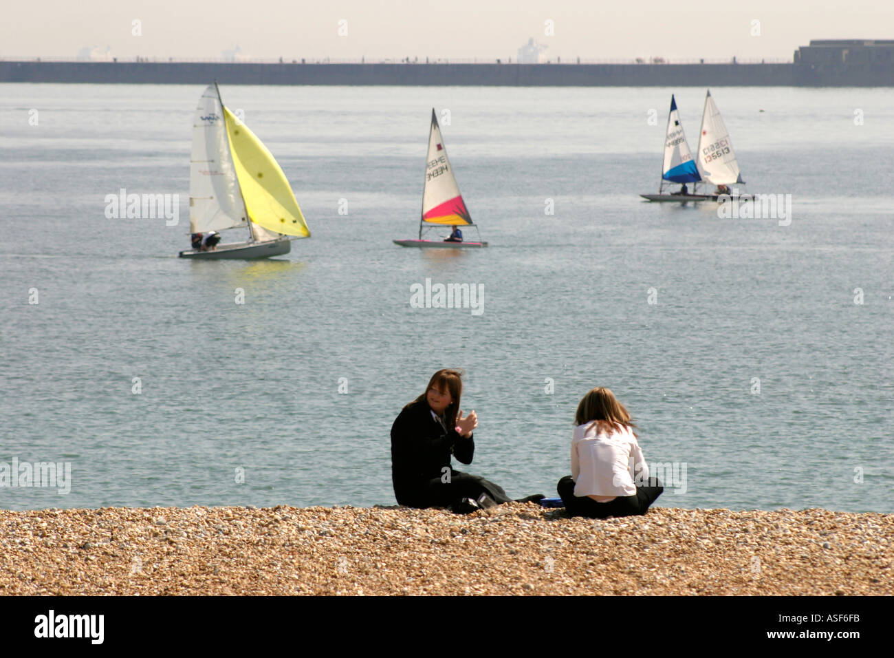 Teenage Girls on Dover Beach watching dinghy sailing in Harbour Stock ...