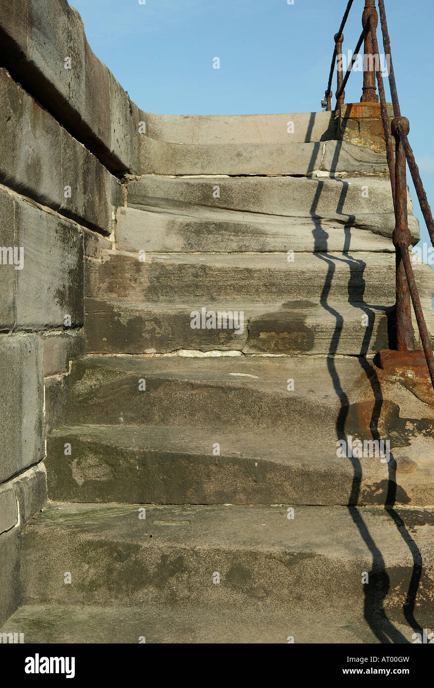 old worn historical stone steps leading upto a harbour wall with ...