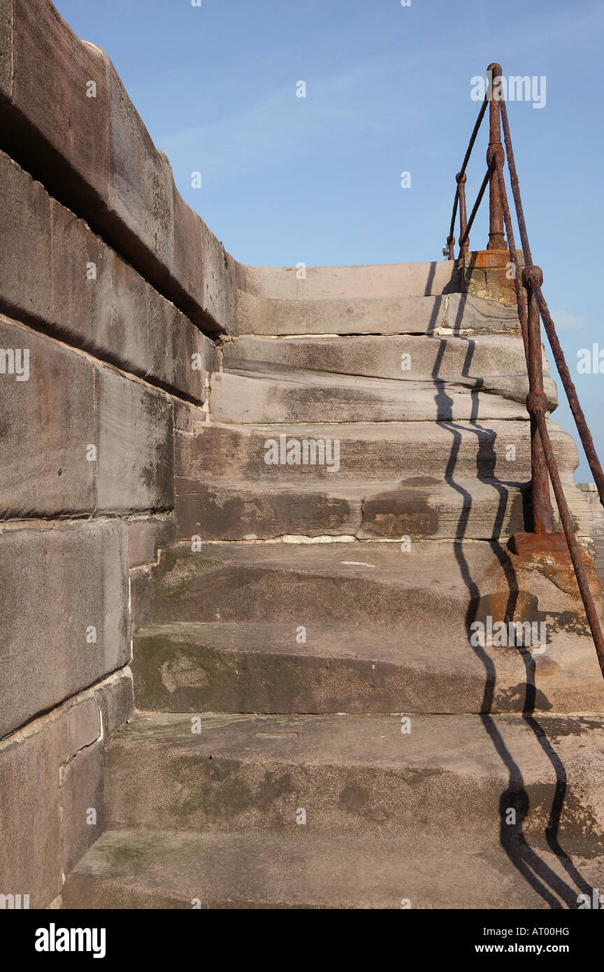 old worn historical stone steps leading upto a harbour wall with ...