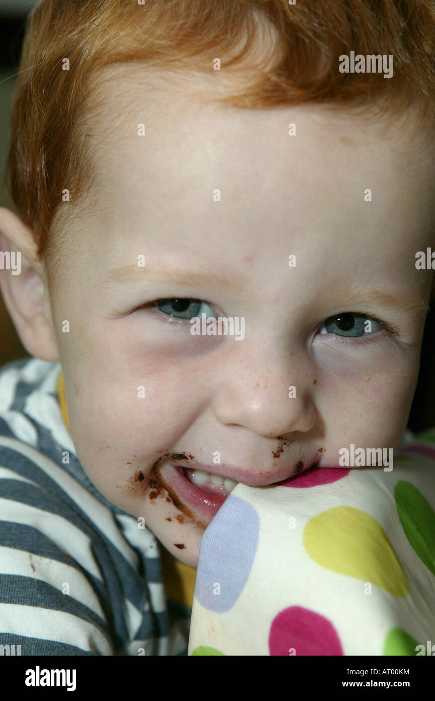 yound child biting into table cloth with chocolate around the mouth and ...