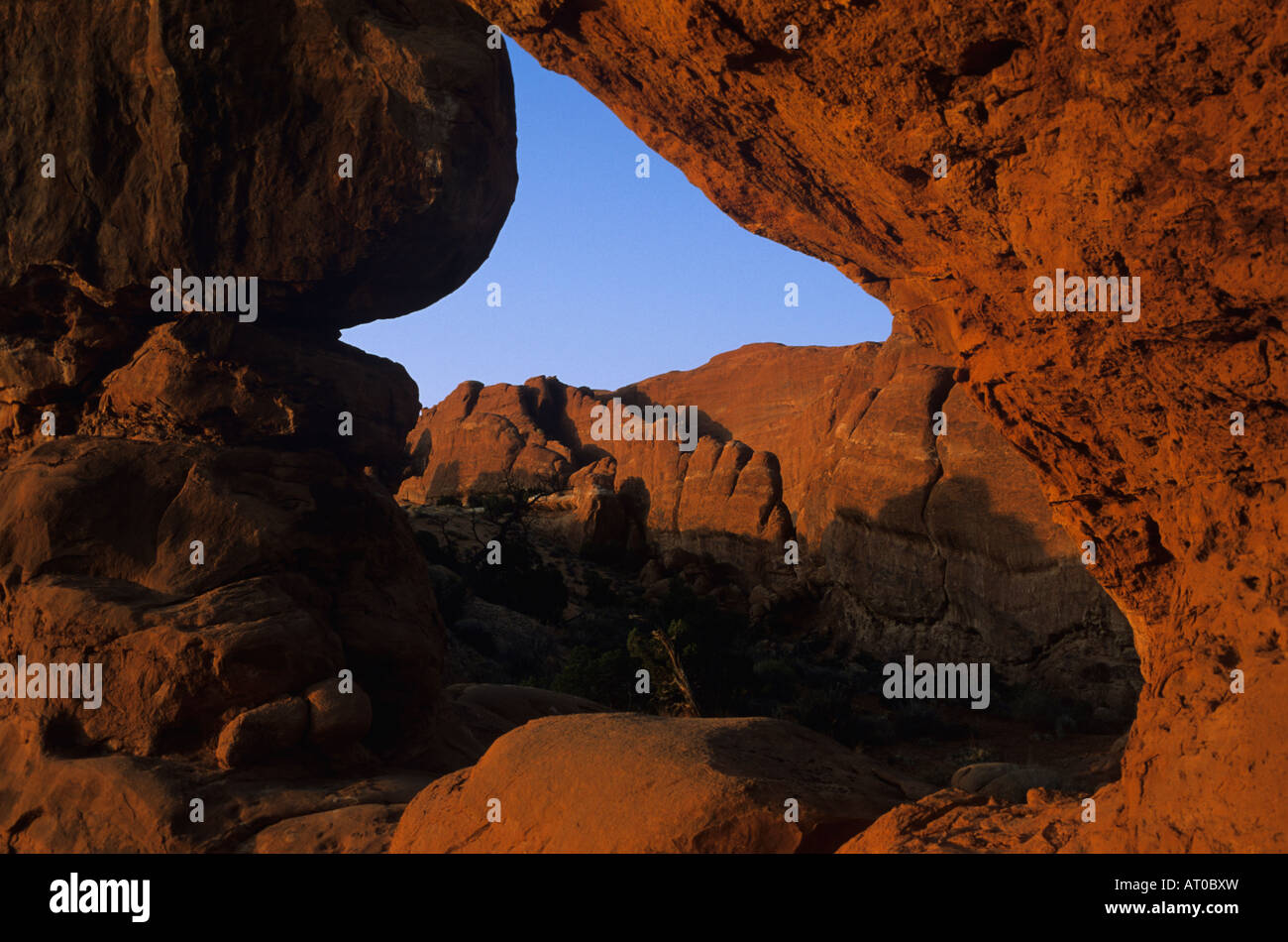 A sandstone window glows red in sunset light, Arches National Park ...