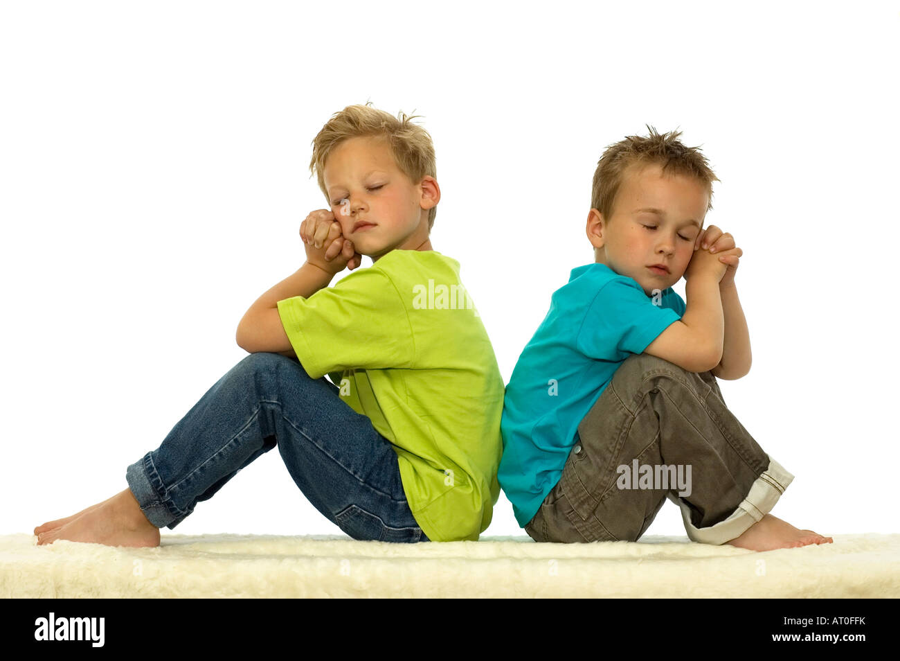 Two friends are praying together sitting with their backs against each ...