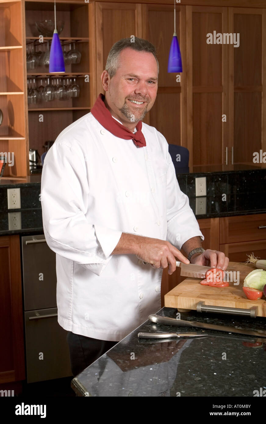 Middle aged male chef standing in kitchen cutting vegetables Stock ...