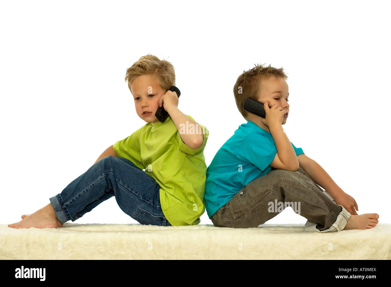 Two friends calling someone on the phone while sitting with their backs ...