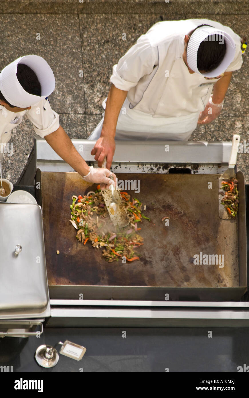 Horizontal aerial close up of two chefs in whites adding ingredients to ...