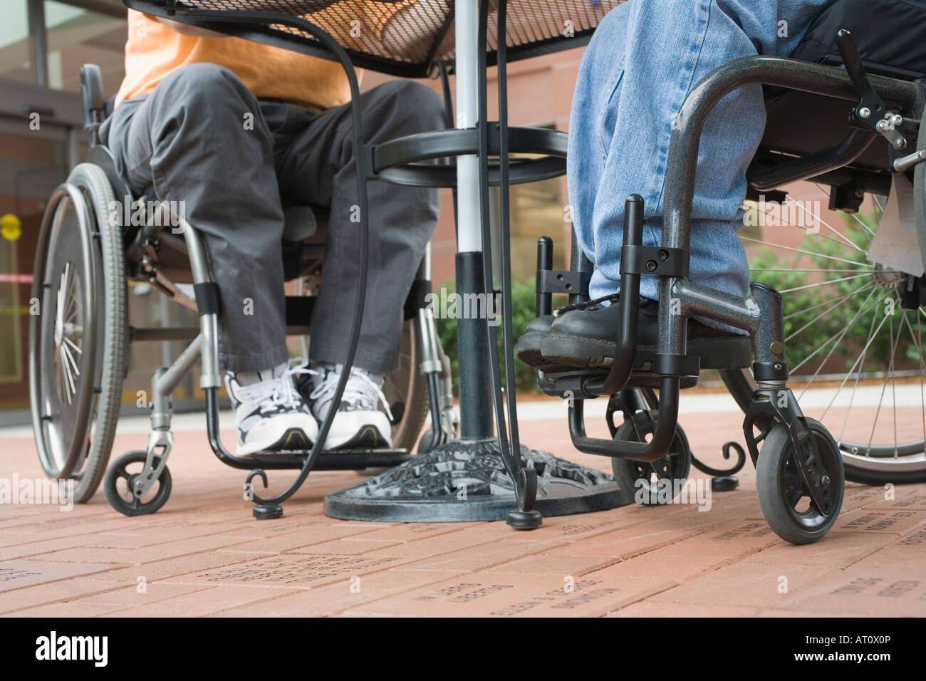 Low section view of two handicapped people sitting in wheelchairs at a ...