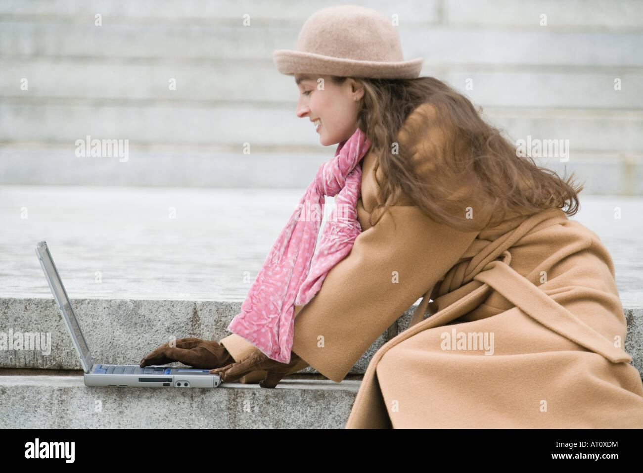 Side profile of a young woman sitting on steps and using a laptop Stock ...