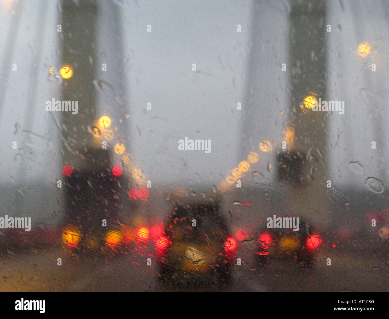 The view out of a car s windscreen of traffic driving through the rain ...