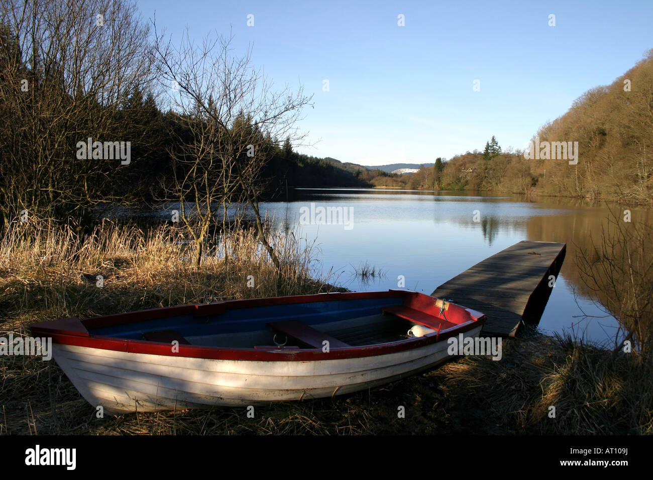 A boat alongside the jetty and waters of Loch Ard in Loch Lomond and ...