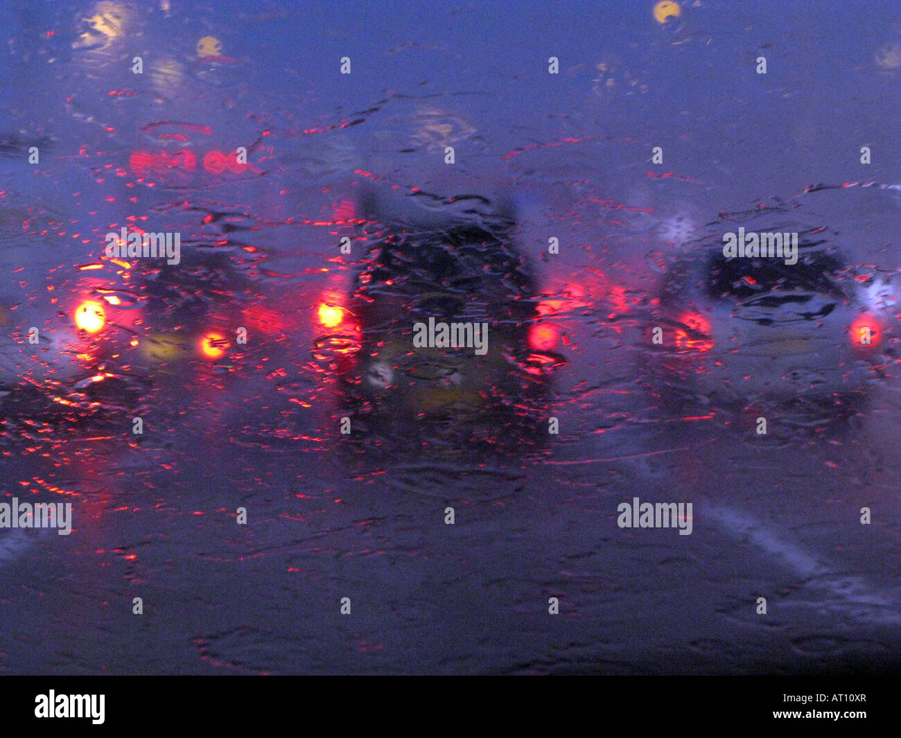 The view out of a car s windscreen of traffic driving through the rain ...