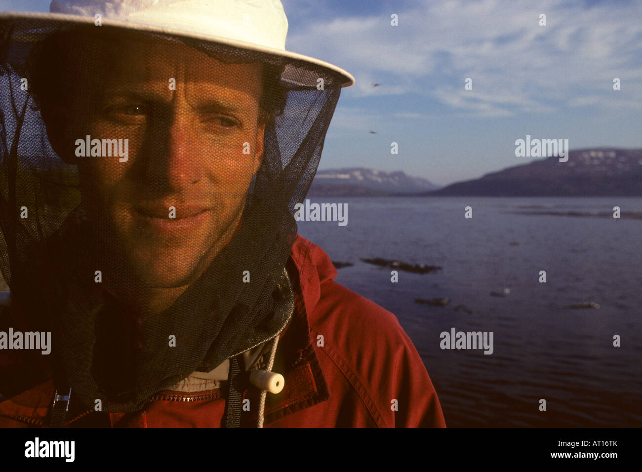 A man wears a mosquito hat to protect his face from swarms of mosquitos ...
