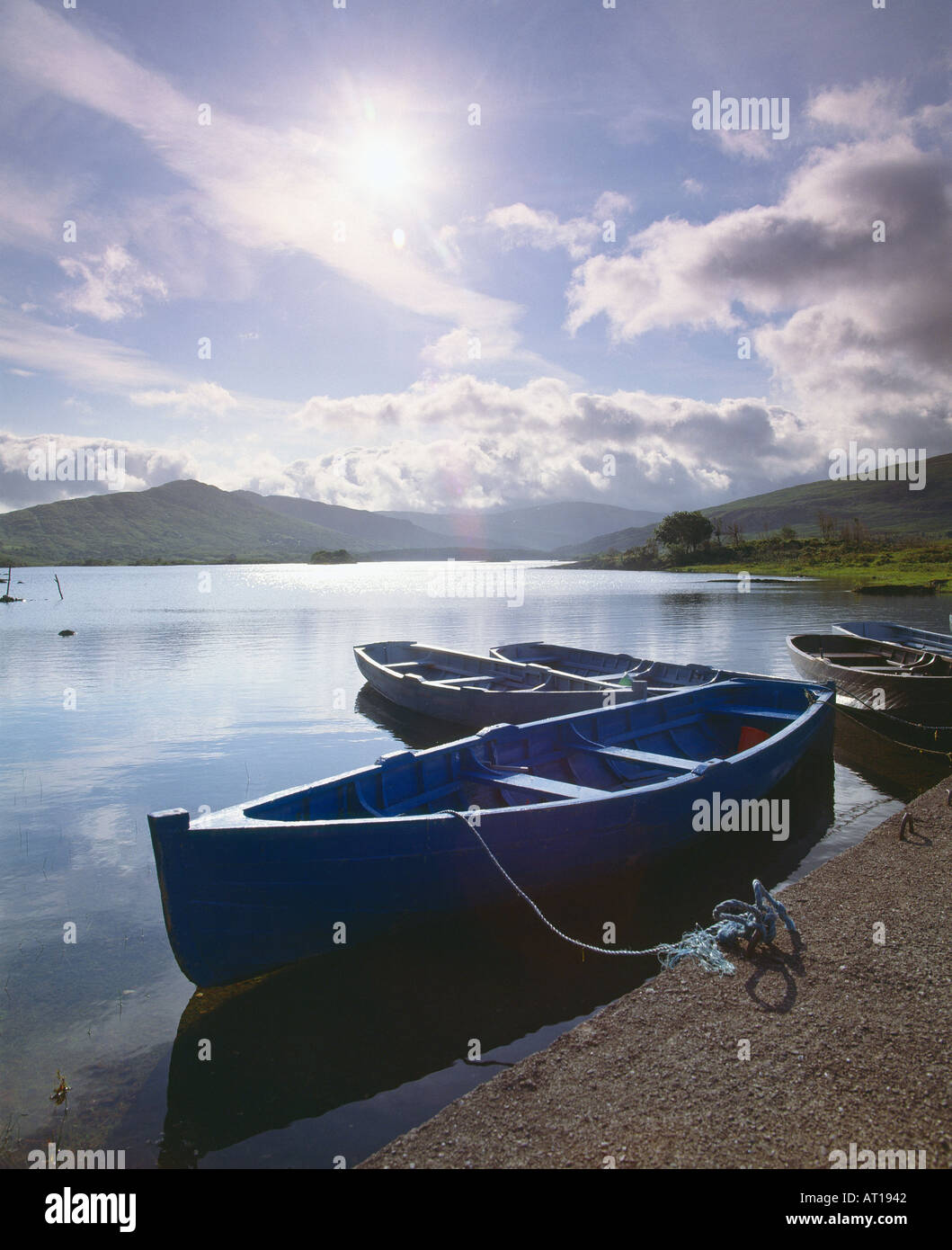 irish inland lake at dawn with small fishing boats tied to pier ...