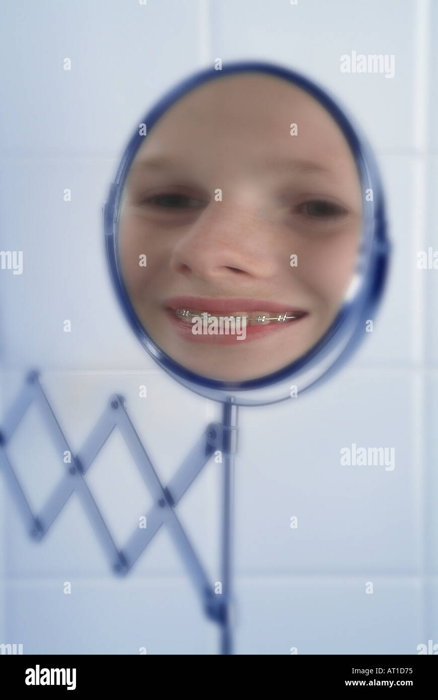teenage boy with teeth brace looking in shaving mirror Stock Photo - Alamy