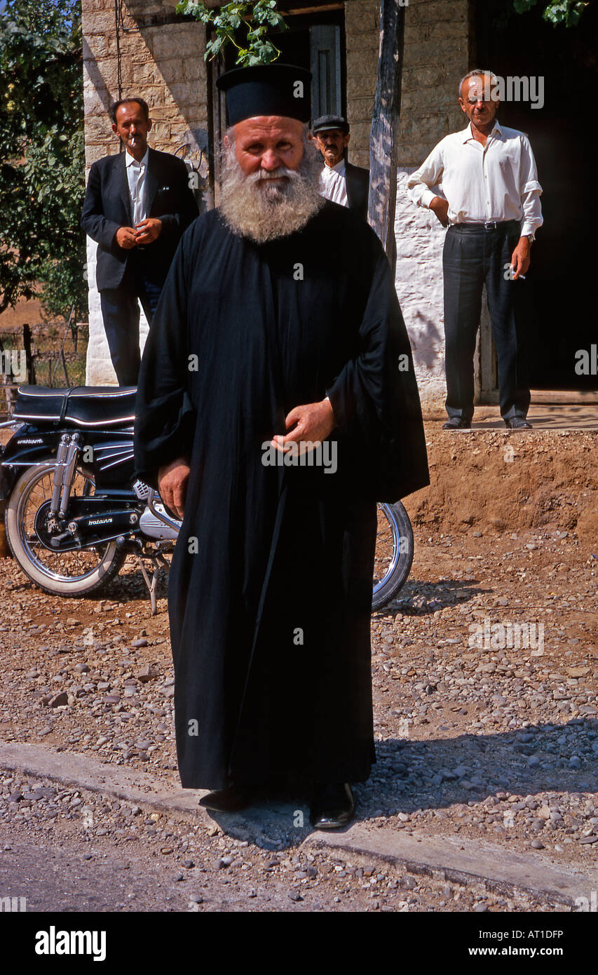 A Greek Orthodox priest with bystanders and a motorcycle behind Stock ...