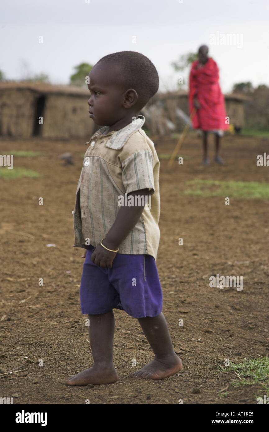 Young Maasai boy in village with father in background Stock Photo - Alamy