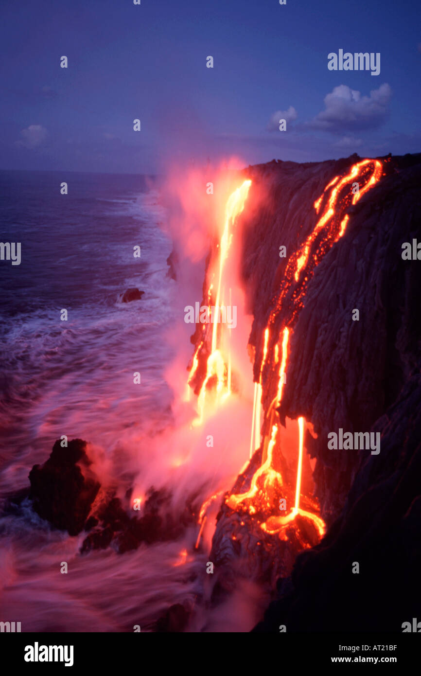 Lava cascades over the sea cliff at sunrise Observers are obscured by ...