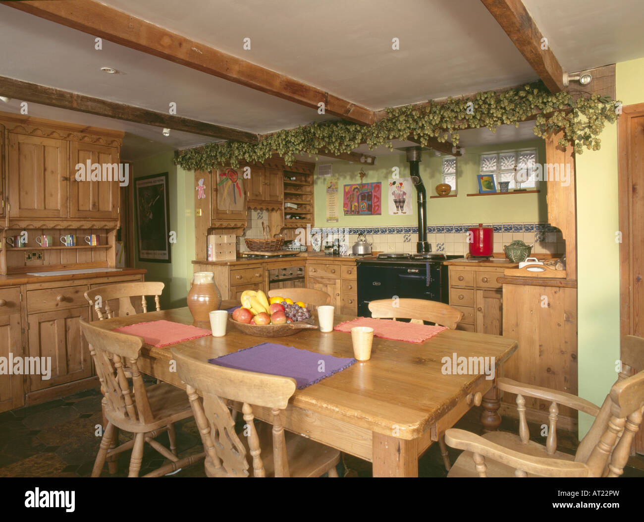 Dried hop garland on ceiling beams on fitted wooden kitchen with pine ...