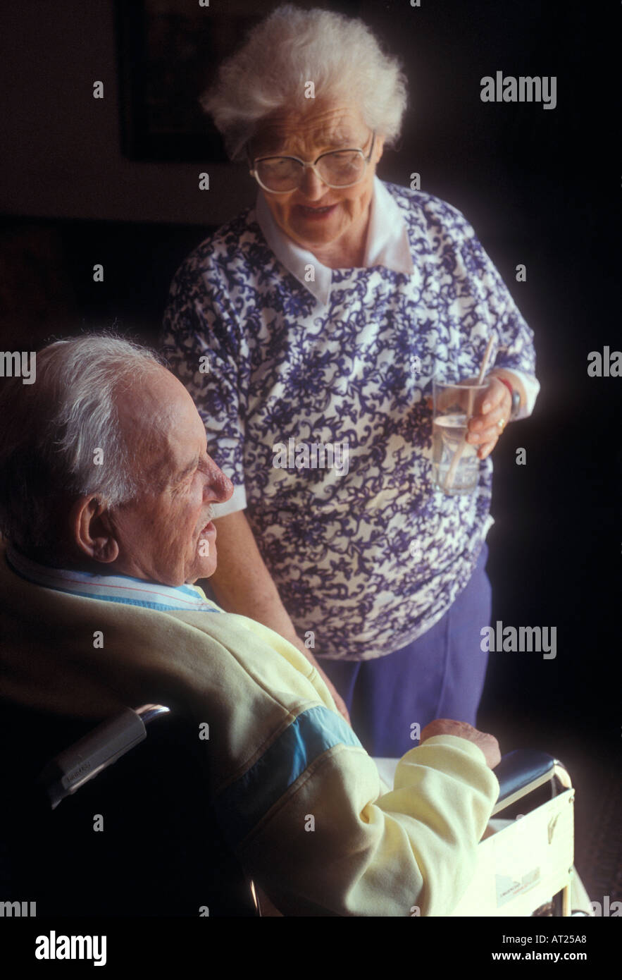 Elderly disabled man in wheelchair with wife carer companion attending ...