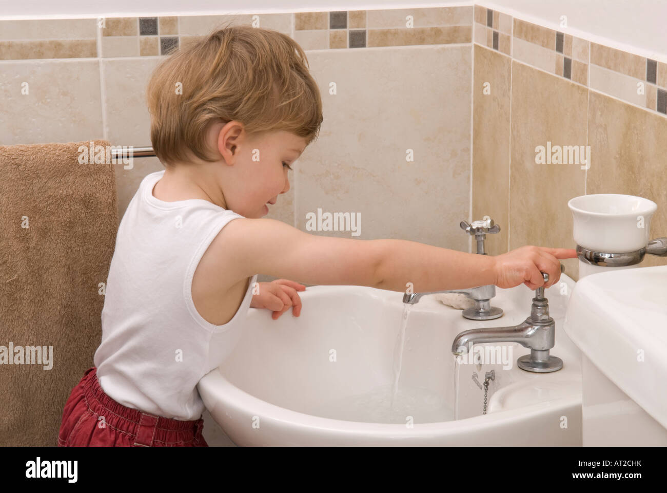boy toddler twenty two months old washing and using taps faucet water ...