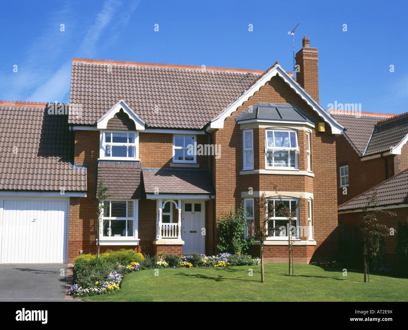 Small lawn in front of traditional detached newbuild house with garage ...