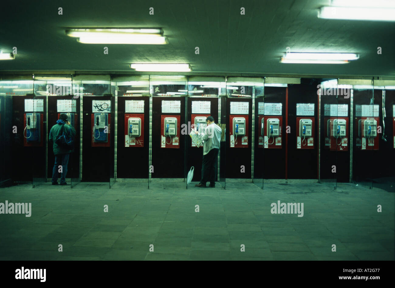 Two men using in a public telephone booth Stock Photo - Alamy