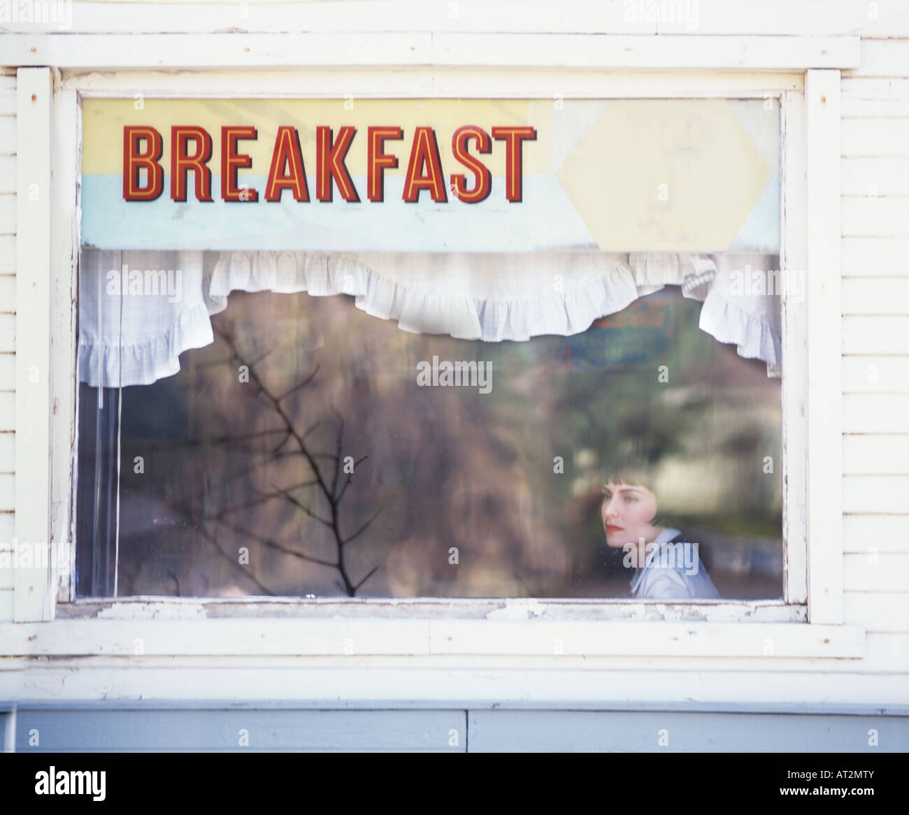fashionable woman eating breakfast in cafe looks through window with ...