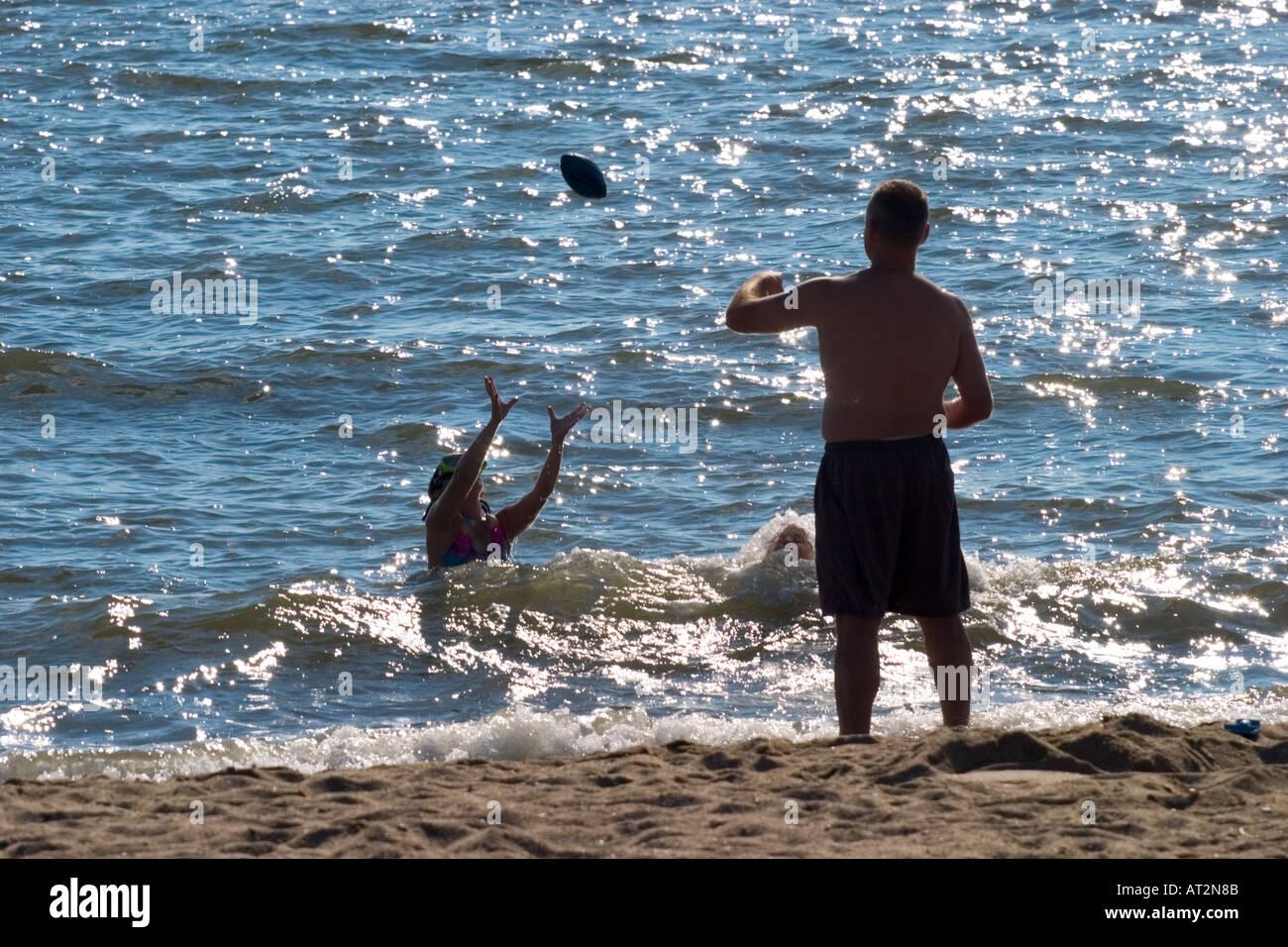 Silhouette of a person on the sand at the beach throwing a football ...