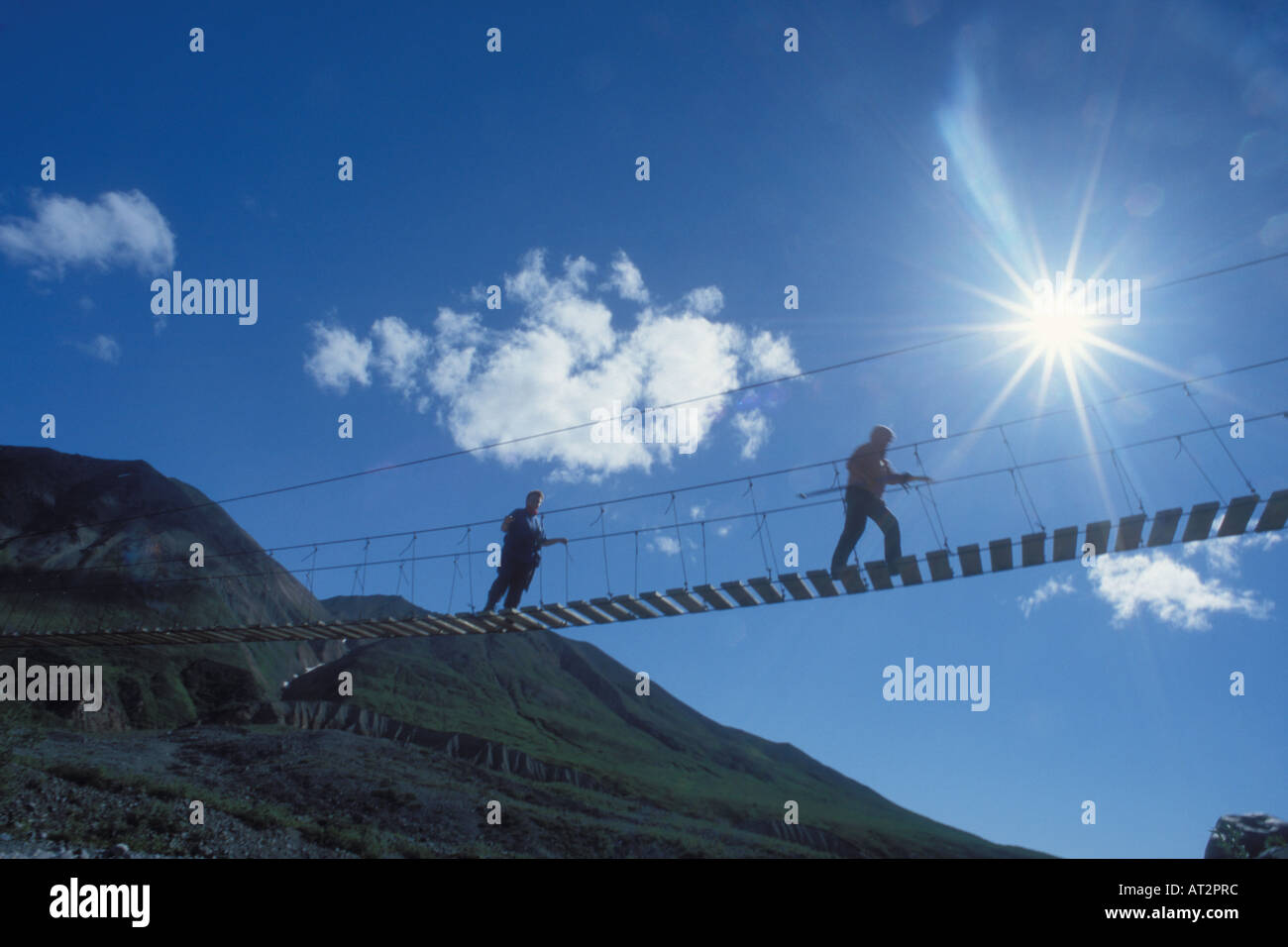 people walking over hanging bridge near Gulkana glacier Alaska Range ...
